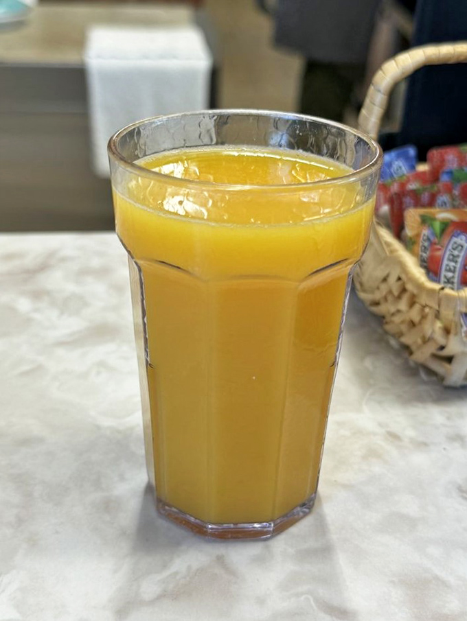 Orange juice served in those classic ridged glasses that somehow make everything taste better, like drinking sunshine after a long Oregon winter.