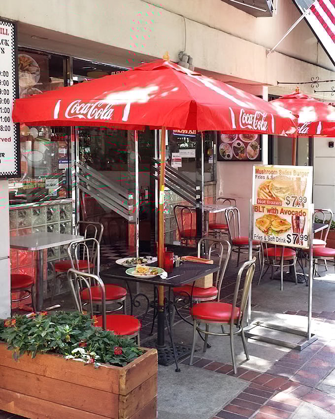 The outdoor seating area, shaded by classic Coca-Cola umbrellas, where your food somehow tastes better with a side of California sunshine.