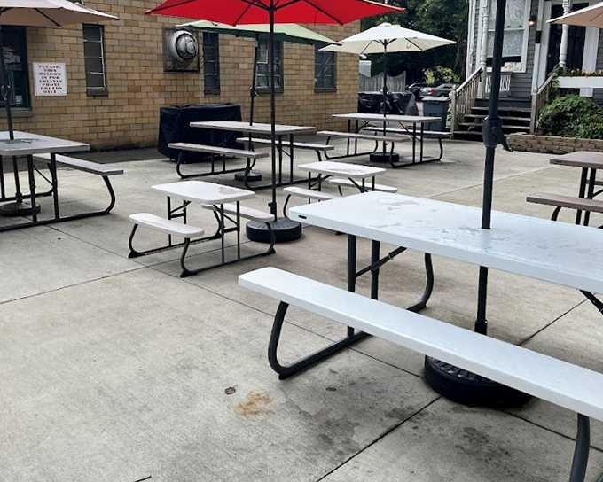 The outdoor seating area waits patiently for summer crowds, those red umbrellas standing guard like cheerful sentinels of sunshine and sprinkles.