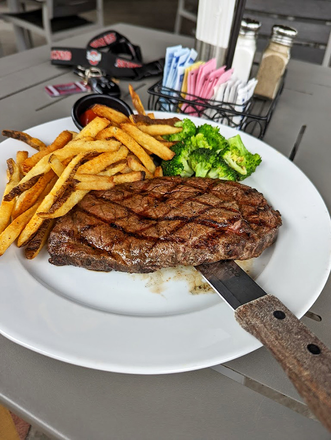 A steak that's achieved that mythical perfect sear, resting beside fries that clearly graduated with honors from Potato University. That knife means business.