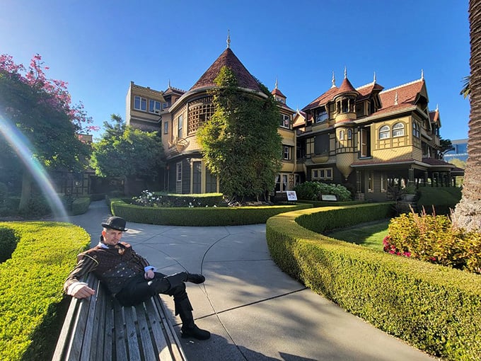The mansion's exterior presents a stunning patchwork of architectural styles, while a visitor takes a moment to contemplate its mysteries.