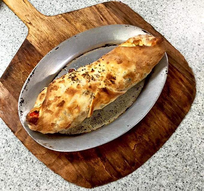 The stromboli&mdash;pizza's sophisticated cousin. Golden-brown exterior hiding a treasure trove of fillings, served on a metal plate that means business.