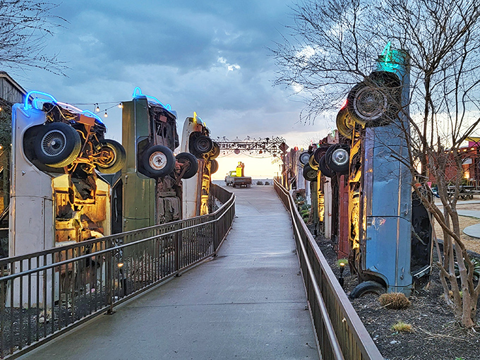 The pathway through Truck Yard feels like walking through a fever dream of automotive nostalgia. Vertical cars create surreal sentinels.