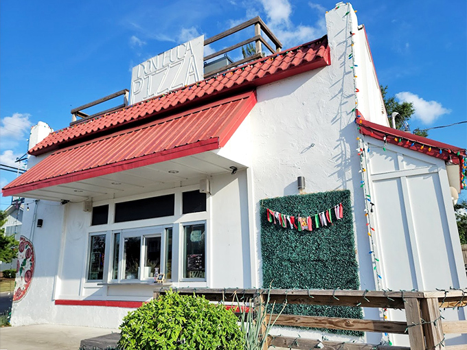 A white-walled pizza oasis with string lights and a red roof. The kind of charming spot that makes you slow down and savor.
