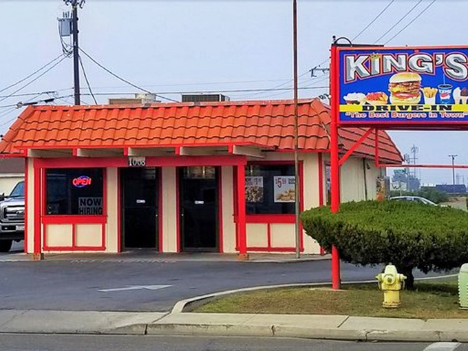 That classic burger sign beckons like a lighthouse for hungry travelers seeking authentic American comfort.
