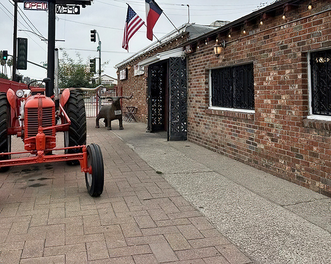 Where Texas meets California—brick walls, iron gates, a red tractor out front, and BBQ that bridges the state divide.