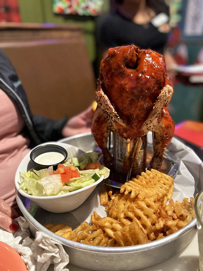 Beer can chicken standing proud like a tiny, delicious monument to culinary ingenuity, surrounded by its crispy waffle fry subjects.