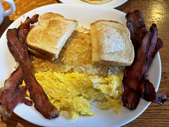 The breakfast trinity: perfectly scrambled eggs, crispy bacon, and toast that didn't forget its butter assignment. Simple perfection on a plate.