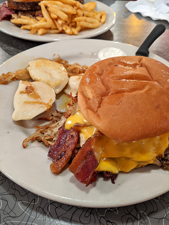 This burger towers with confidence, stacked high enough to require strategic planning and possibly architectural engineering to consume properly.