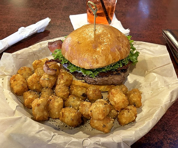 A burger that demands to be photographed before eaten, paired with tater tots that make you wonder why you ever grew up. Pure comfort on parchment paper.