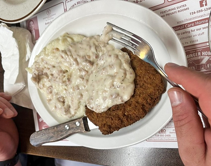 Chicken fried steak smothered in creamy gravy &ndash; a dish that transforms ordinary mornings into extraordinary comfort food experiences.