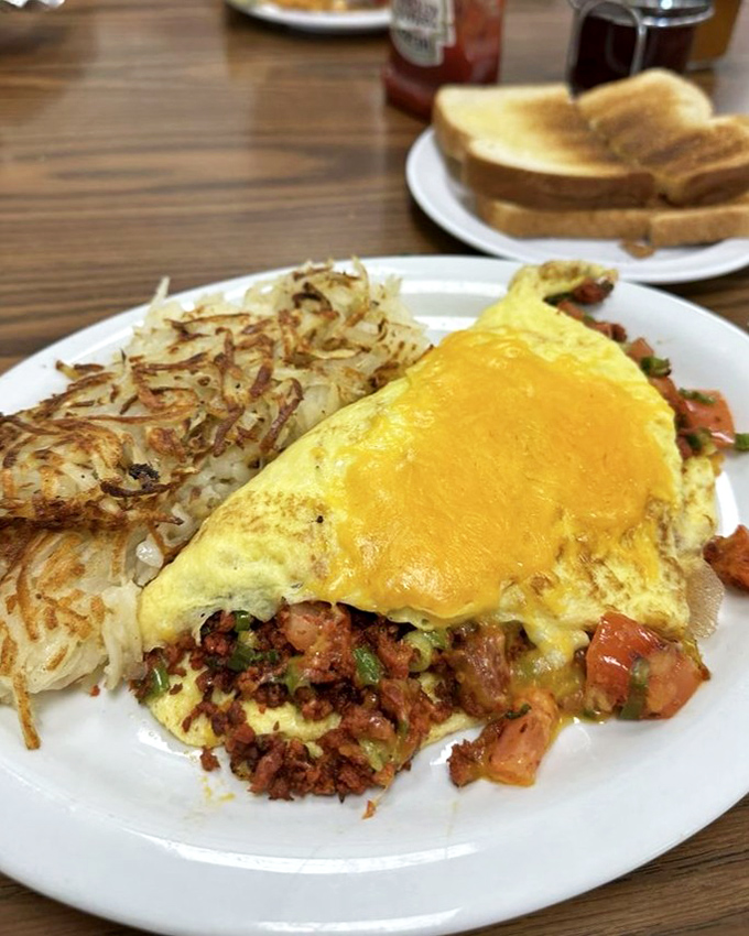 Behold the omelet of champions: Chorizo bringing its smoky swagger to eggs, while those hash browns achieve the perfect crisp-to-tender ratio that haunts breakfast dreams.