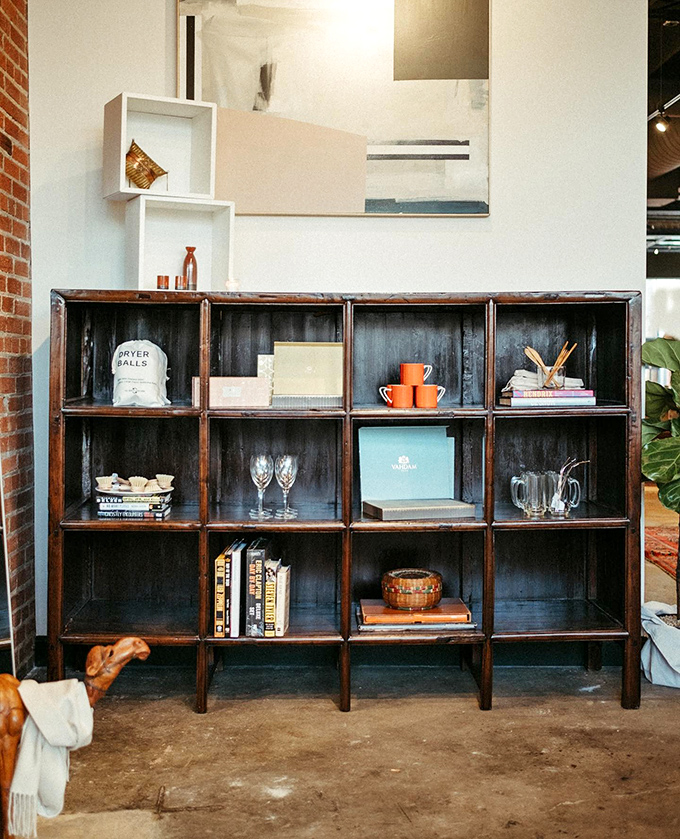This weathered wooden shelving unit tells stories of past lives while showcasing carefully curated treasures for future homes.