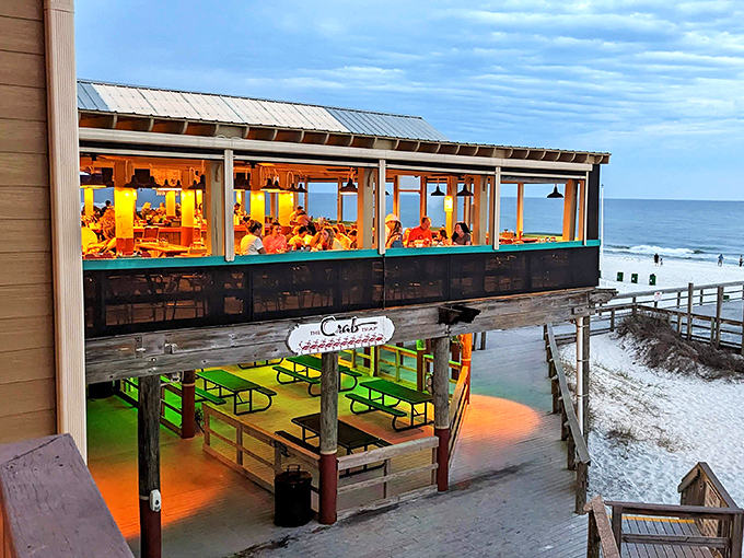Sunset transforms the Crab Trap into a glowing fishbowl perched above the sand, serving dinner with a side of spectacle.