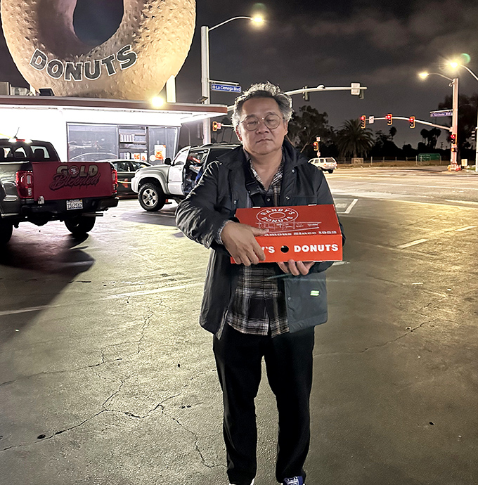 The look of pure donut satisfaction. Nothing says "mission accomplished" quite like clutching that iconic red box under the glow of the giant donut.