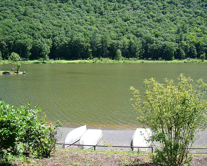Boats wait patiently by the shore, ready to carry adventurers across waters that reflect the endless green of surrounding mountains.