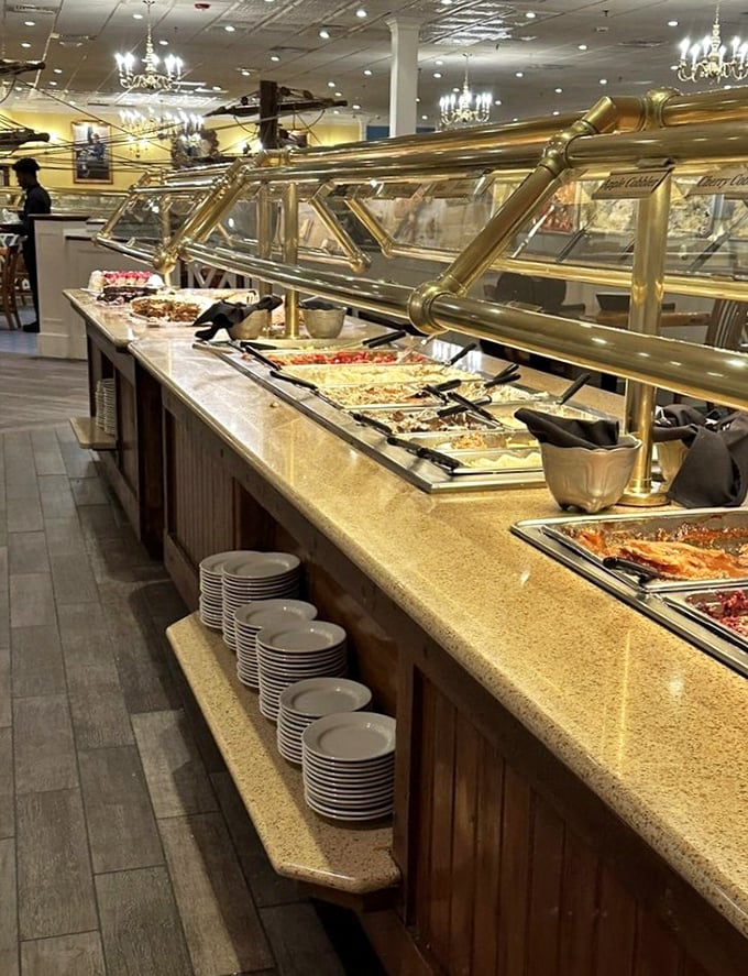The buffet stretches like a golden-hued seafood highway, with stacks of plates standing by like eager passengers ready for the journey.