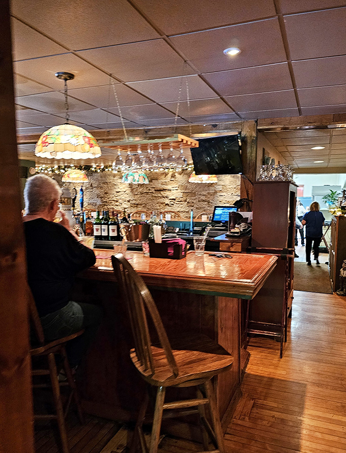 The bar area where locals gather and visitors become regulars, under the warm glow of stained glass and stories shared over perfectly mixed Manhattans.