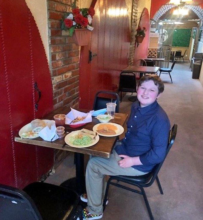 A young diner grins at his feast&mdash;proof that appreciating good Mexican food is a skill best learned early in life.