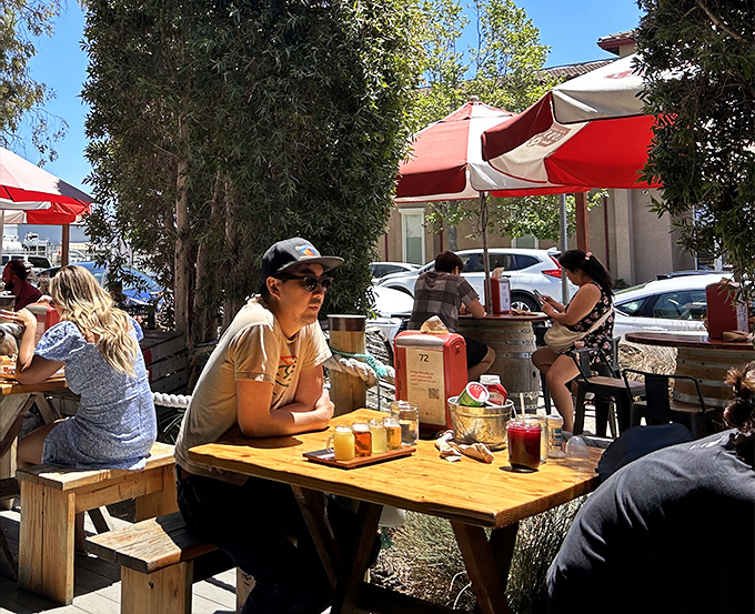 California sunshine meets East Coast flavors as diners enjoy the outdoor seating. Those flight glasses suggest someone's wisely sampling multiple beverage options.