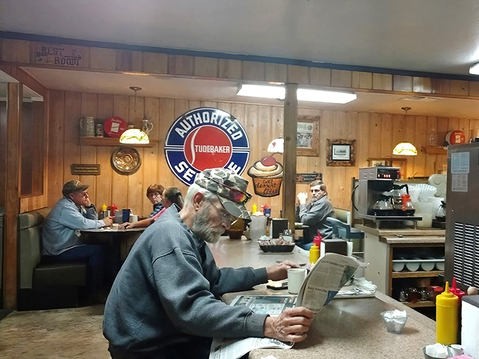 The counter regulars have probably solved all of America's problems over coffee by now. The Studebaker sign watches over their deliberations.