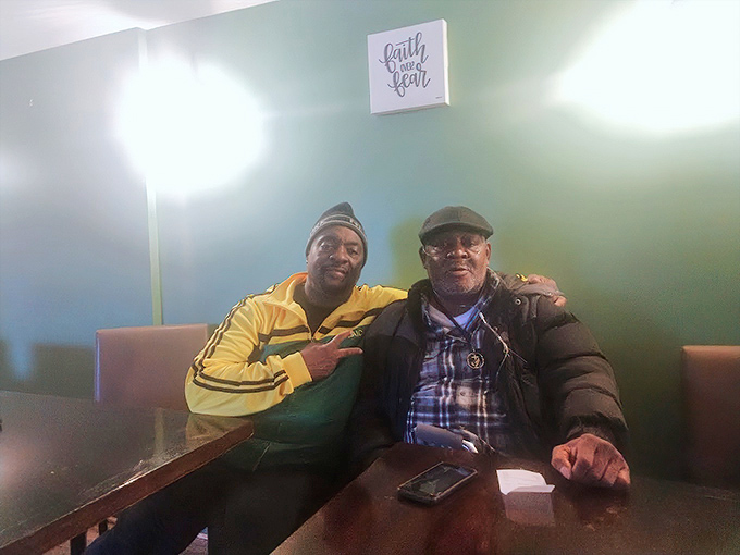 The "Faith and Fear" sign watches over diners sharing stories and meals. In soul food restaurants, strangers often leave as friends.