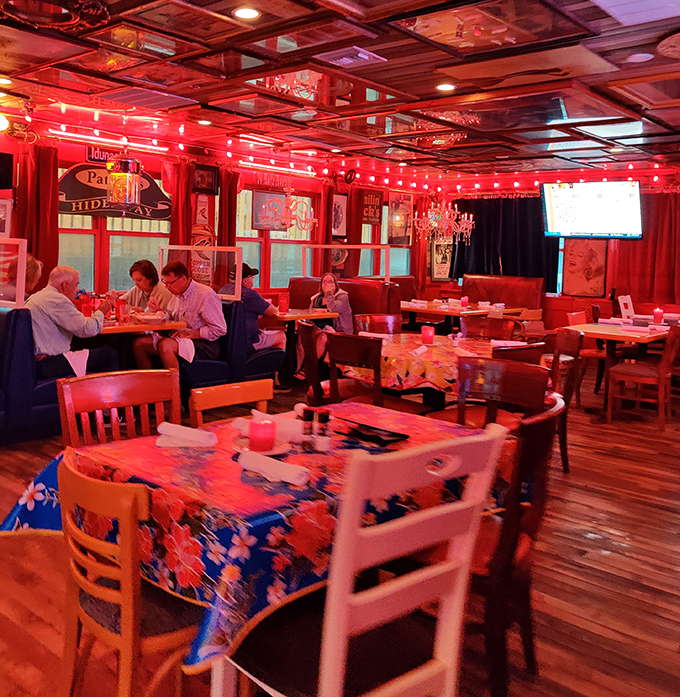 The crimson glow bathes diners in flattering light, turning an ordinary Tuesday dinner into what feels like a scene from a Wes Anderson film set in paradise.