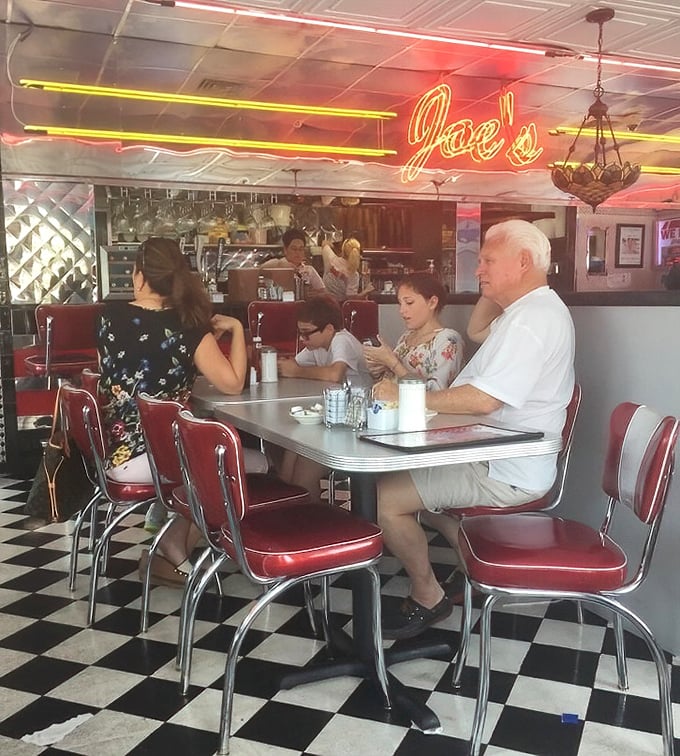 Where strangers become neighbors over coffee refills. The neon glow of "Joe's" overhead is the universal signal for "you belong here."
