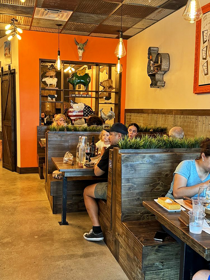 Wooden booths separated by planters create intimate dining islands. The corrugated metal ceiling adds industrial charm without trying too hard.