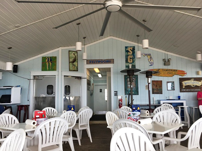Coastal-blue walls, weathered wood, and ceiling fans spinning island time&mdash;an interior designed by necessity rather than Instagram trends.