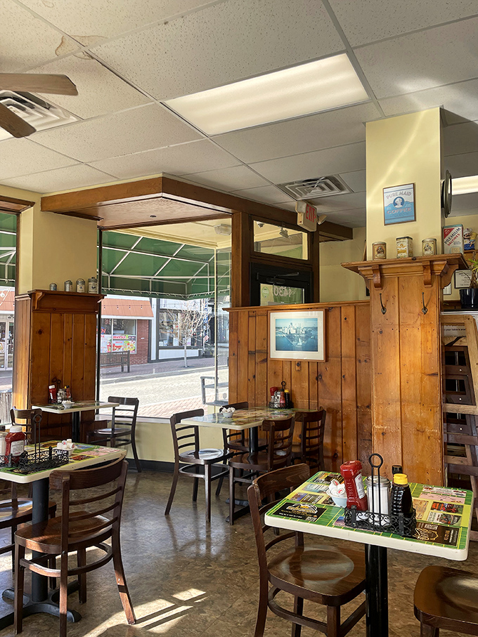 Warm wood paneling and tables set for comfort, not pretension. Sunlight streams in, highlighting decades of breakfast memories made here.