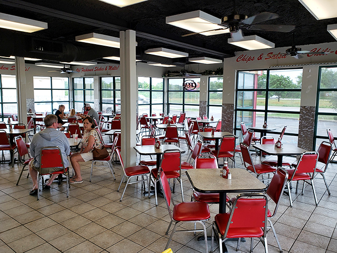 Red chairs pop against white tables in a dining room where conversations flow as freely as the refills. Texas hospitality in its natural habitat.