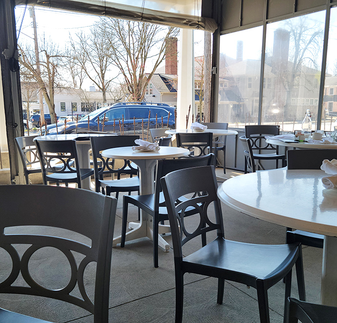 Winter light streams through windows in this cozy corner, where tables await conversations that will inevitably pause when the food arrives.