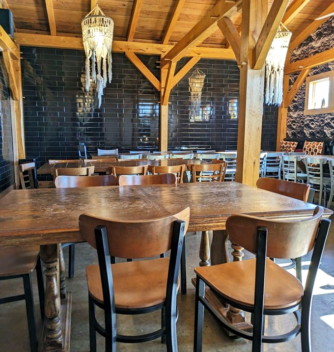 Exposed wooden beams, sleek black tile, and macram&eacute; chandeliers create a dining space that feels both rustic and surprisingly sophisticated.