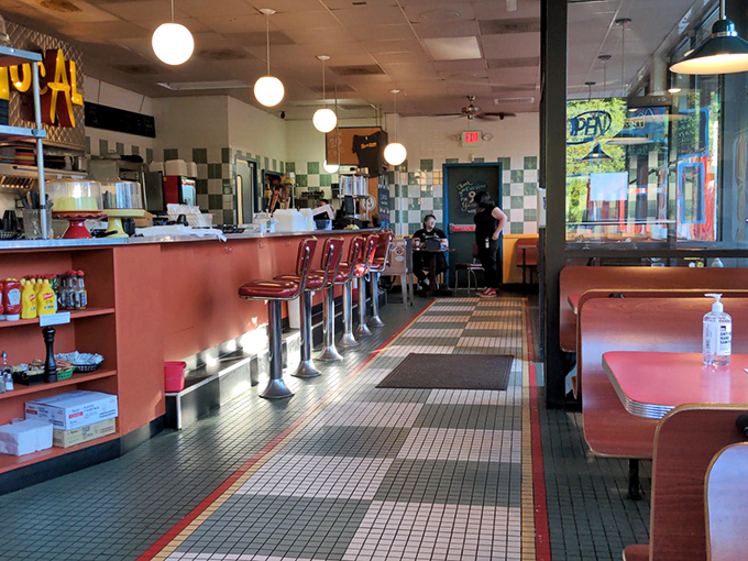 The quintessential diner interior where the checkered floor and coral counter have witnessed countless coffee refills and life-changing conversations.