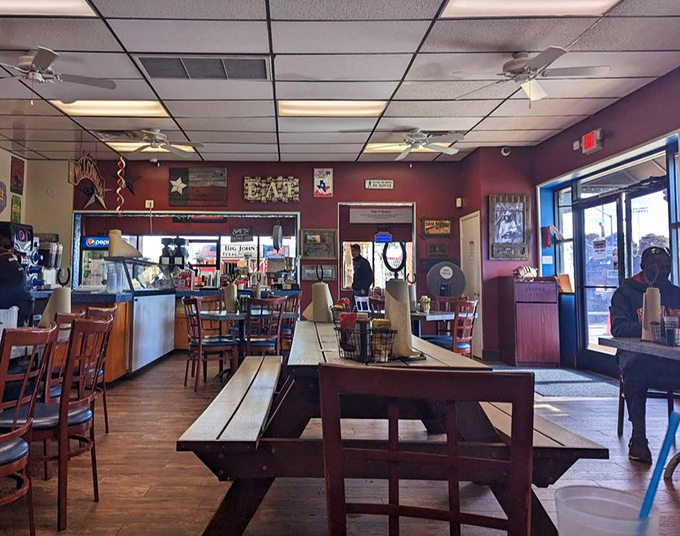The dining area speaks the universal language of Texas: wooden tables, red walls, and the subtle suggestion to loosen your belt.