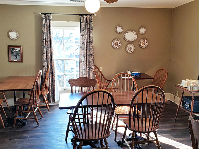 Sunlight streams through vintage curtains onto Windsor chairs and decorative plates&mdash;a dining room that feels more like coming home than eating out.