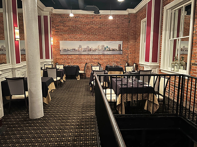 Brick walls and city views create a dining space that feels both historic and contemporary. Those tables have heard more dinner confessions than a priest.