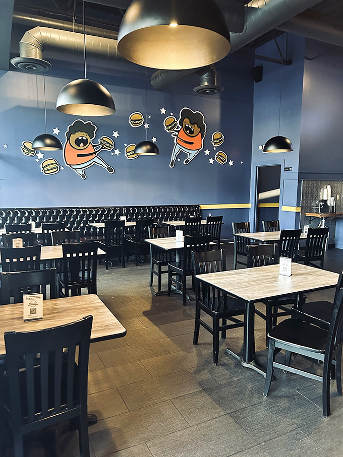 Whimsical burger characters dance across blue walls, celebrating what you're about to experience. They know what's coming, and they're excited for you.