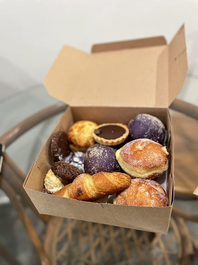 A box of joy containing what appears to be a sugar-dusted donut, chocolate crinkle cookies, and an almond pastry. Breakfast of champions, lunch of heroes.