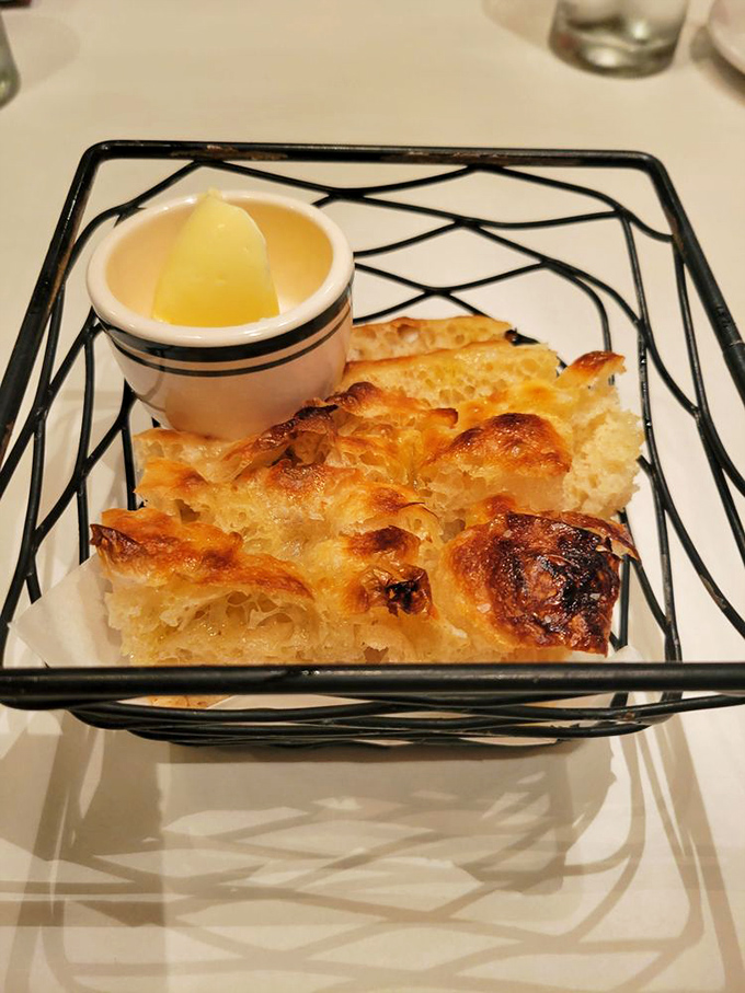 Focaccia that's achieved bread perfection&mdash;golden, airy interior with a crust that crackles just right, served with what appears to be honey butter.