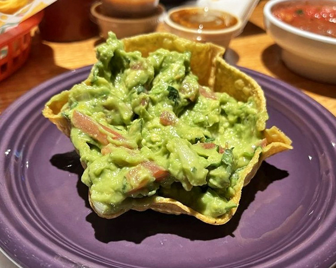 Fresh guacamole served in a crispy tortilla bowl - because presentation matters, even in casual dining establishments.