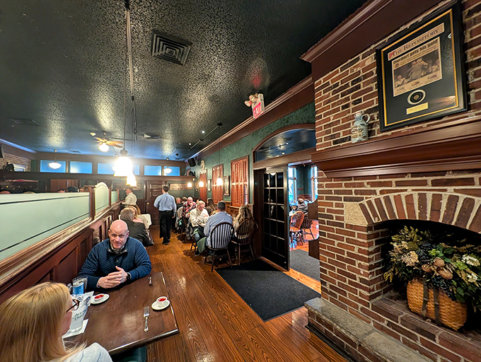 The brick fireplace and warm wood tones create a dining atmosphere that makes strangers feel like neighbors and neighbors feel like family.