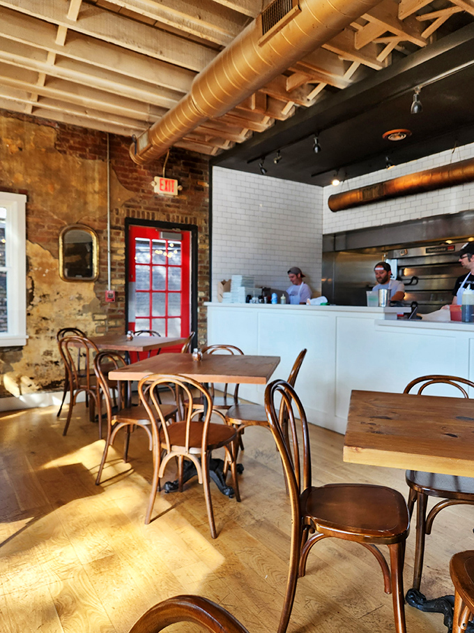 Sunlight streams through windows onto wooden tables while the open kitchen promises transparency in both design and cooking philosophy.