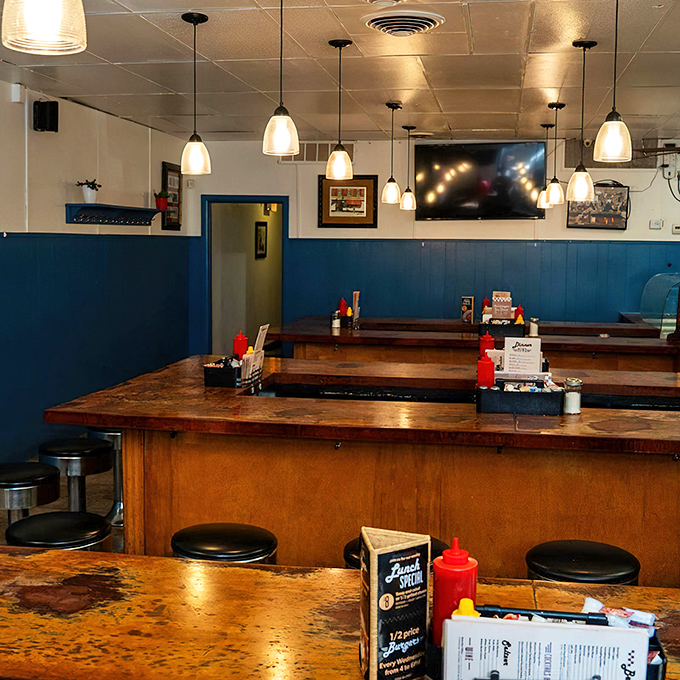 Blue wainscoting meets warm wood counters in this classic diner setup. The pendant lights cast just enough glow to make everyone look like they got enough sleep.