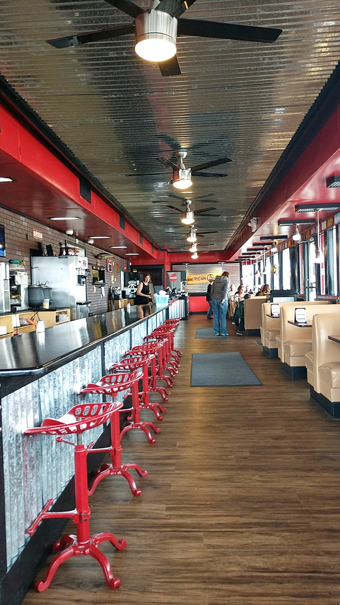 The long counter and red stools invite lingering conversations about which barbecue item deserves your next order.