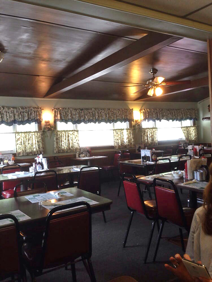 Wooden ceiling beams, floral curtains, and red chairs create that perfect "everybody knows your order" atmosphere that chain restaurants try desperately to replicate.