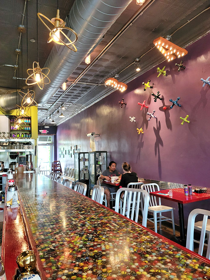 Purple walls set the stage while atomic light fixtures dangle overhead&mdash;this isn't just decor, it's conversation fodder between bites.