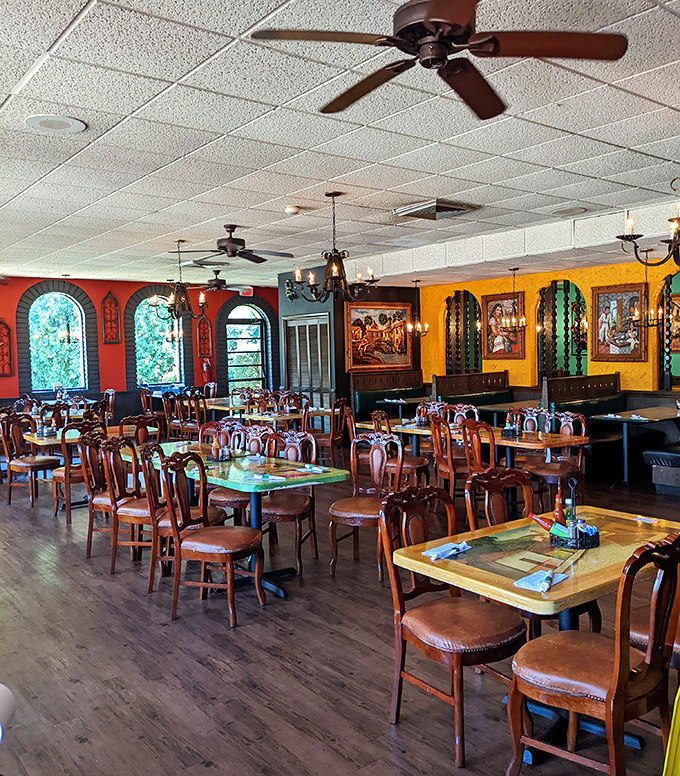 Ceiling fans lazily spin above a dining room where wooden chairs await hungry patrons. The stained glass windows add unexpected elegance.