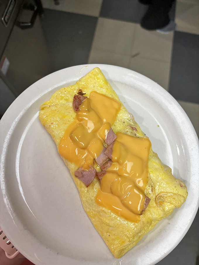 This omelet isn't just breakfast—it's edible sunshine drizzled with cheese sauce that makes Monday mornings slightly more bearable.